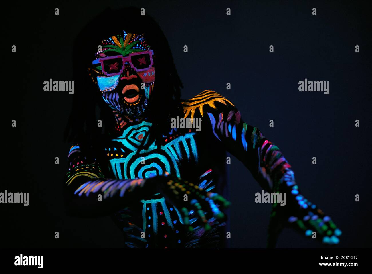 handsome black african man in fluorescent patterns dancing in ...