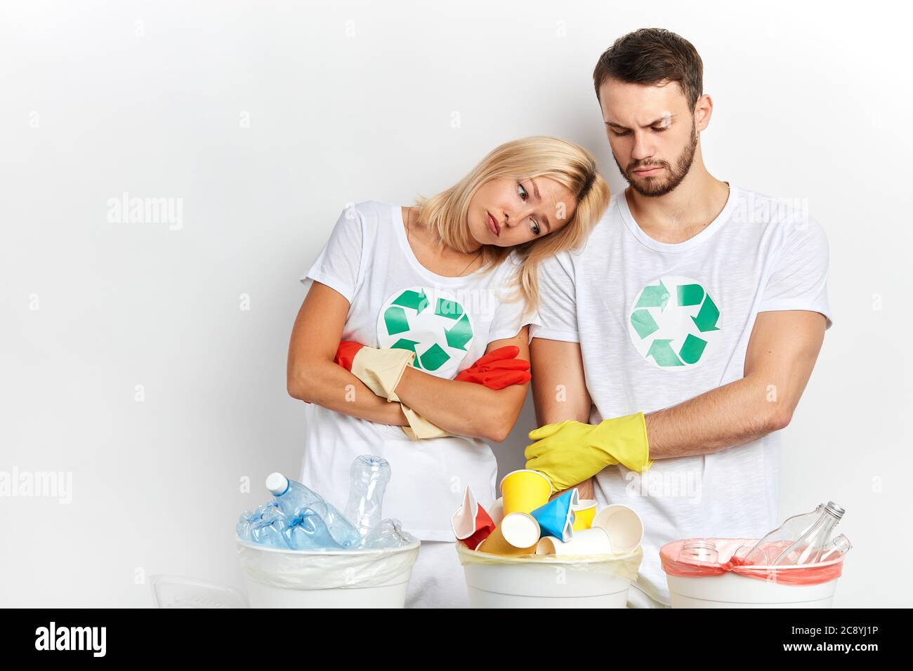 Portrait of a disappointed tired volunteers in white t-shirts removing ...