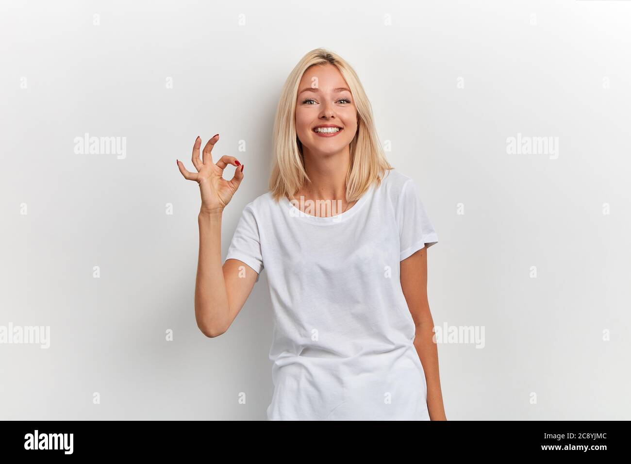 Portrait of a pretty positive smiling woman showing okay sign and over ...