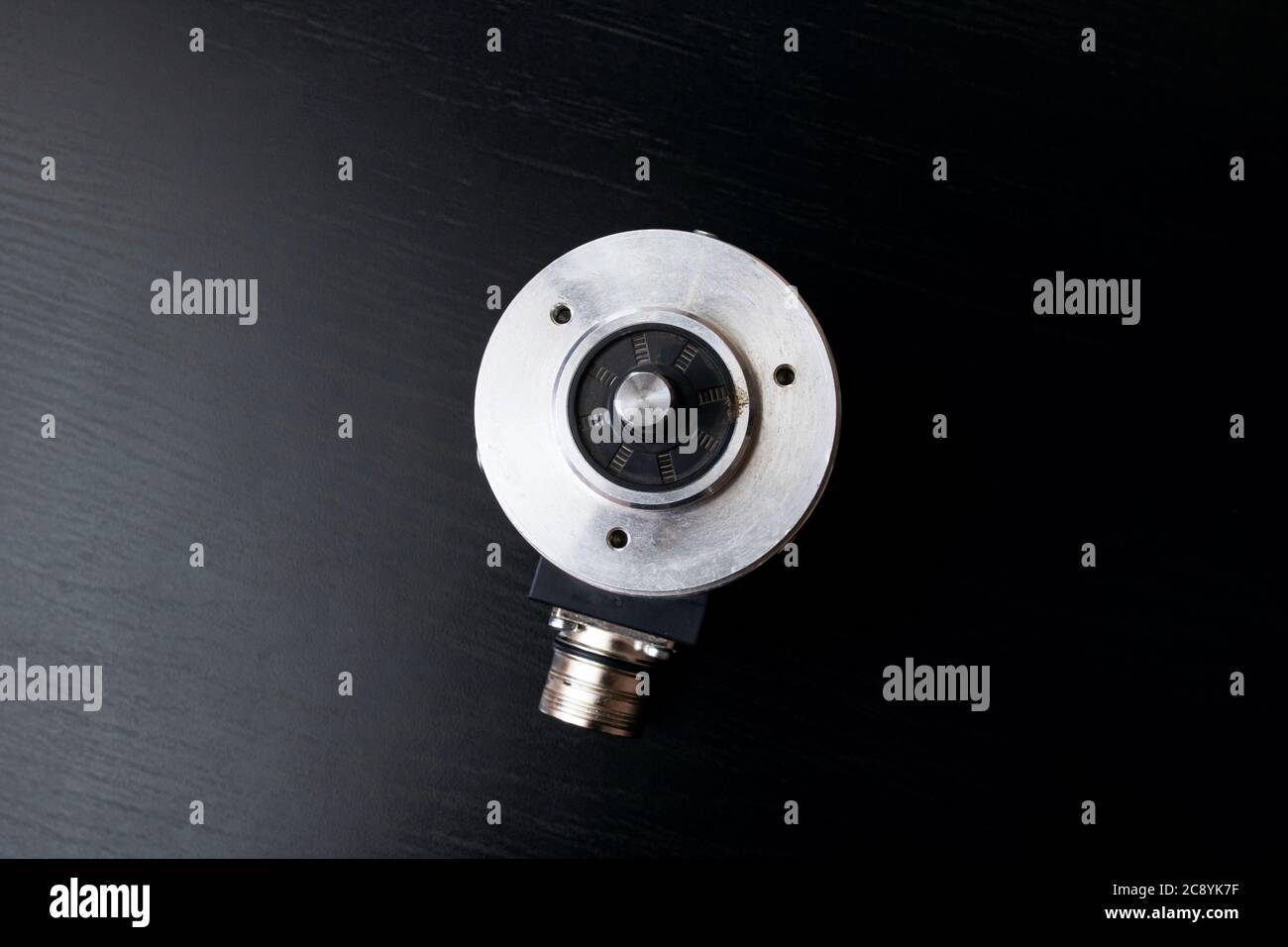 Metal encoder on a black wooden table, top view Stock Photo - Alamy