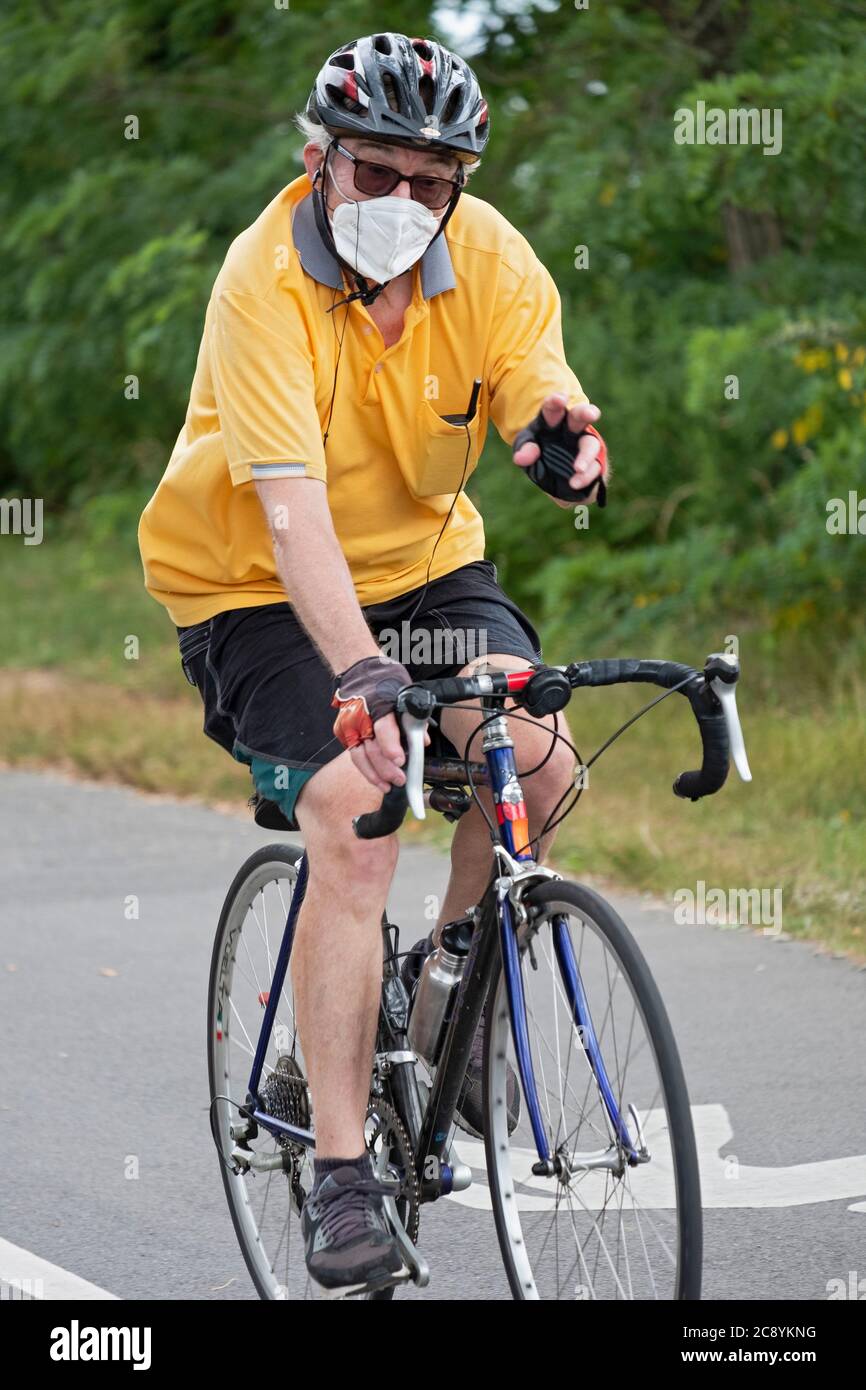 A cheerful bike rider wearing a mask & helmet waves at this ...