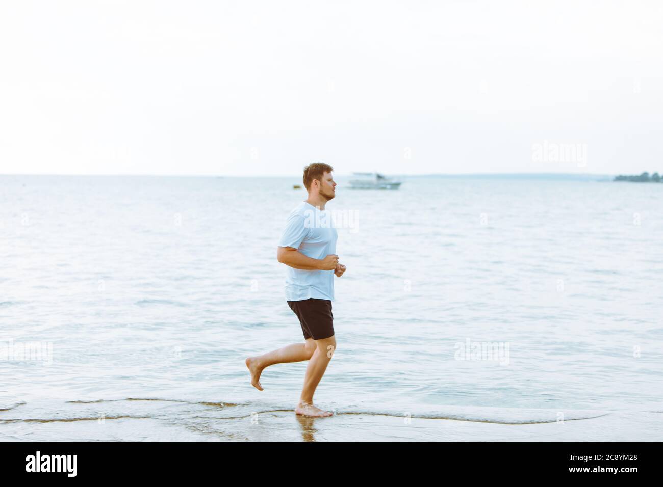 Man barefoot running beach handsome hi-res stock photography and images ...