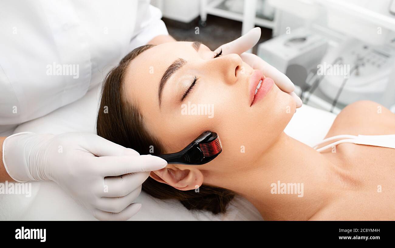 Beautician doing skin treatment using a microneedle derma roller. Woman ...