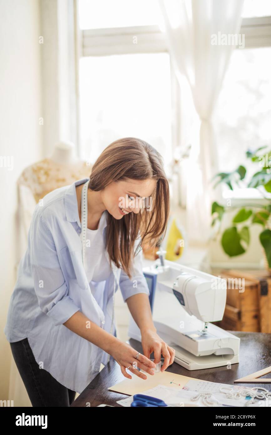 Young female dressmaker works in a well-lit sunny cozy studio Stock ...