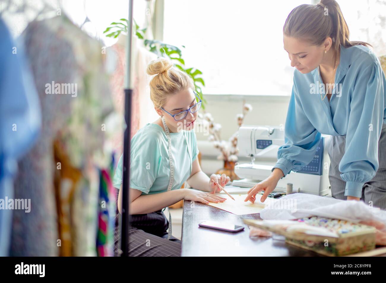 Cute female seamstress discusses with the client sketch of custom made ...