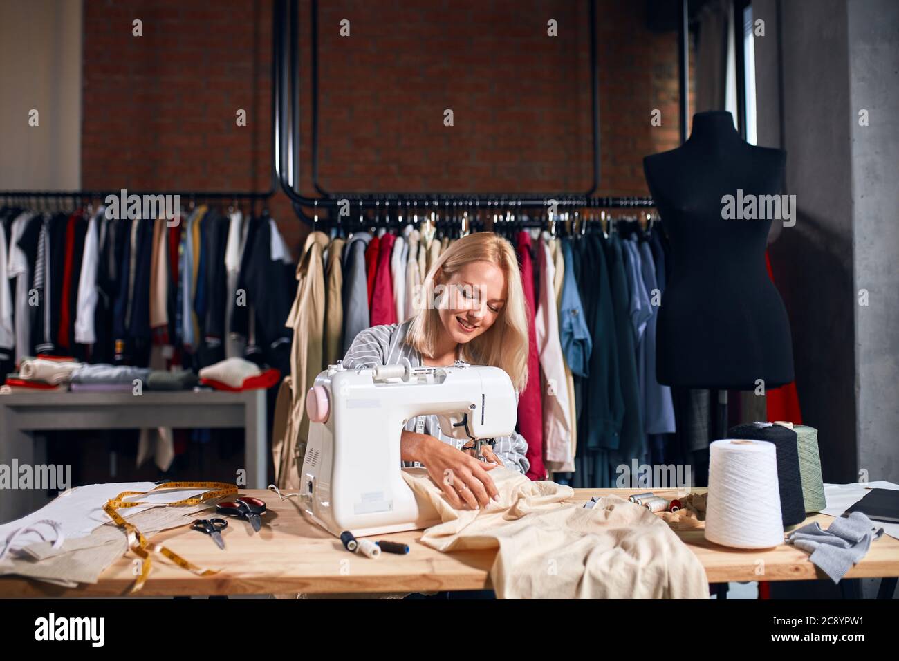 pleasant smiling woman decorating clothes with detailed embroidery work ...