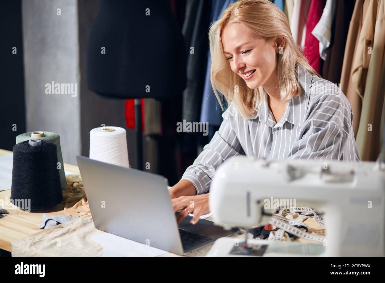 smiling positive tailor chatting with her boyfriend online, tailor ...