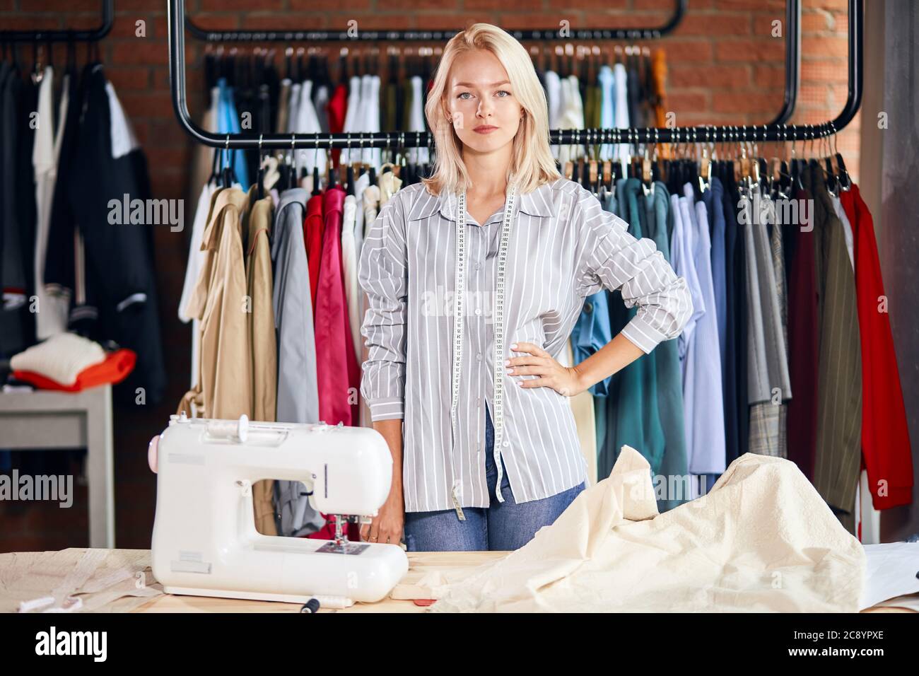 confident serious dressmaker with a hand on her hip posing to the ...