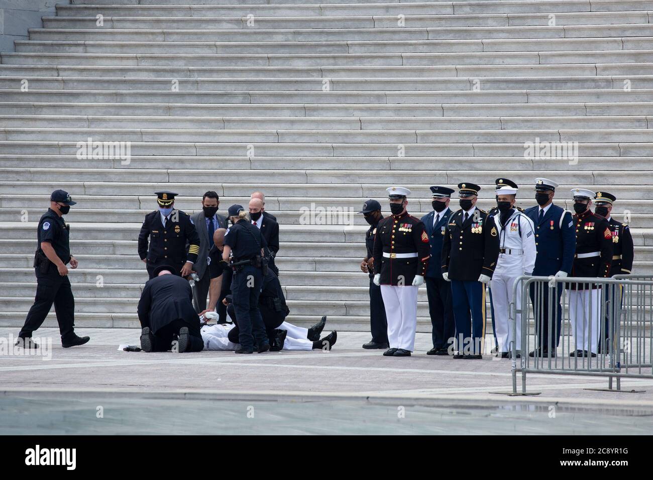 A member of the Military Honor Guard receives help from police officers ...