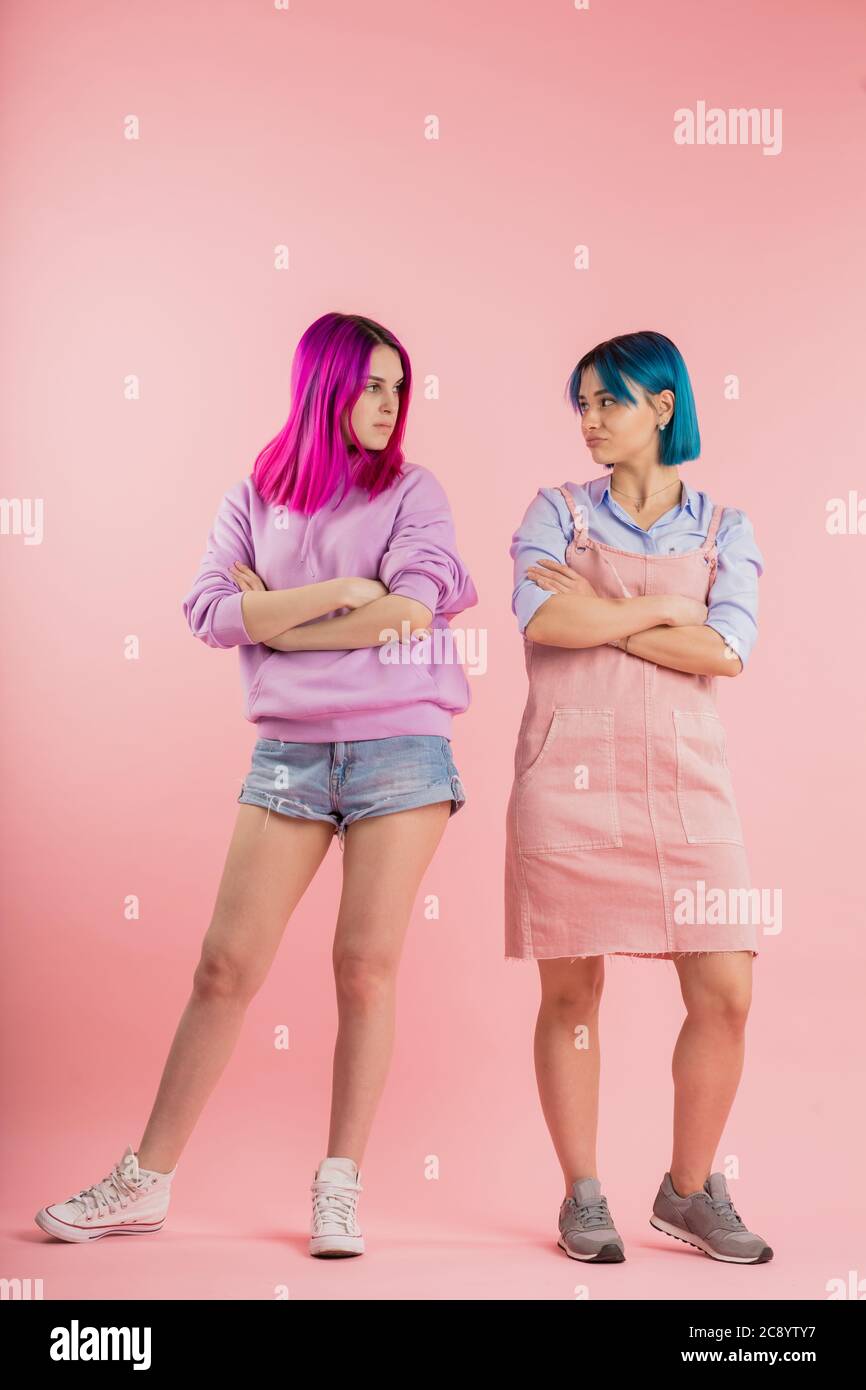 Two stylish beautiful women angry with each other. pink background ...
