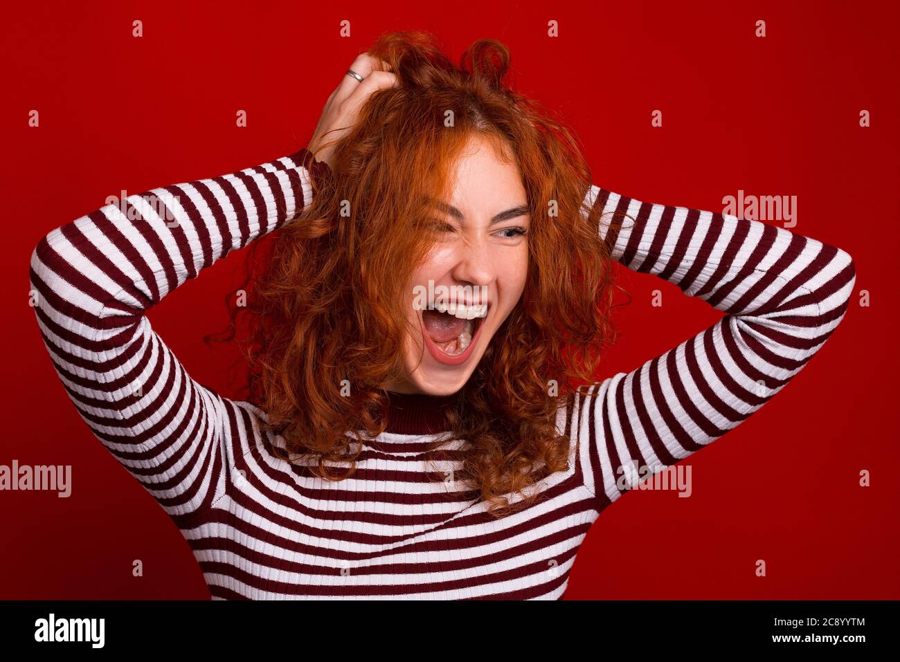 Photo of crazy screaming red head girl, standong over red background ...