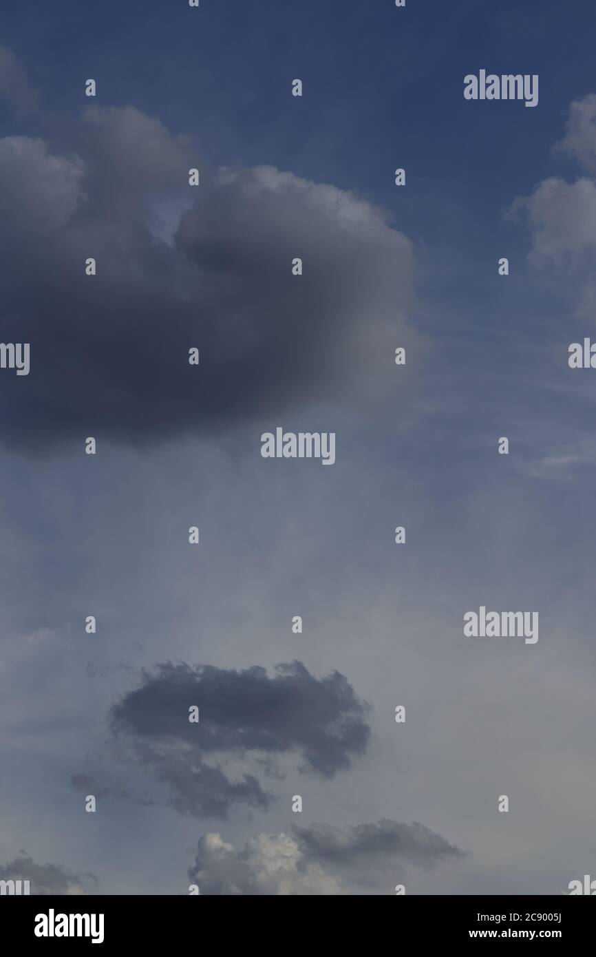 Fluffy shaded gray clouds floating under a misty blue sky Stock Photo ...