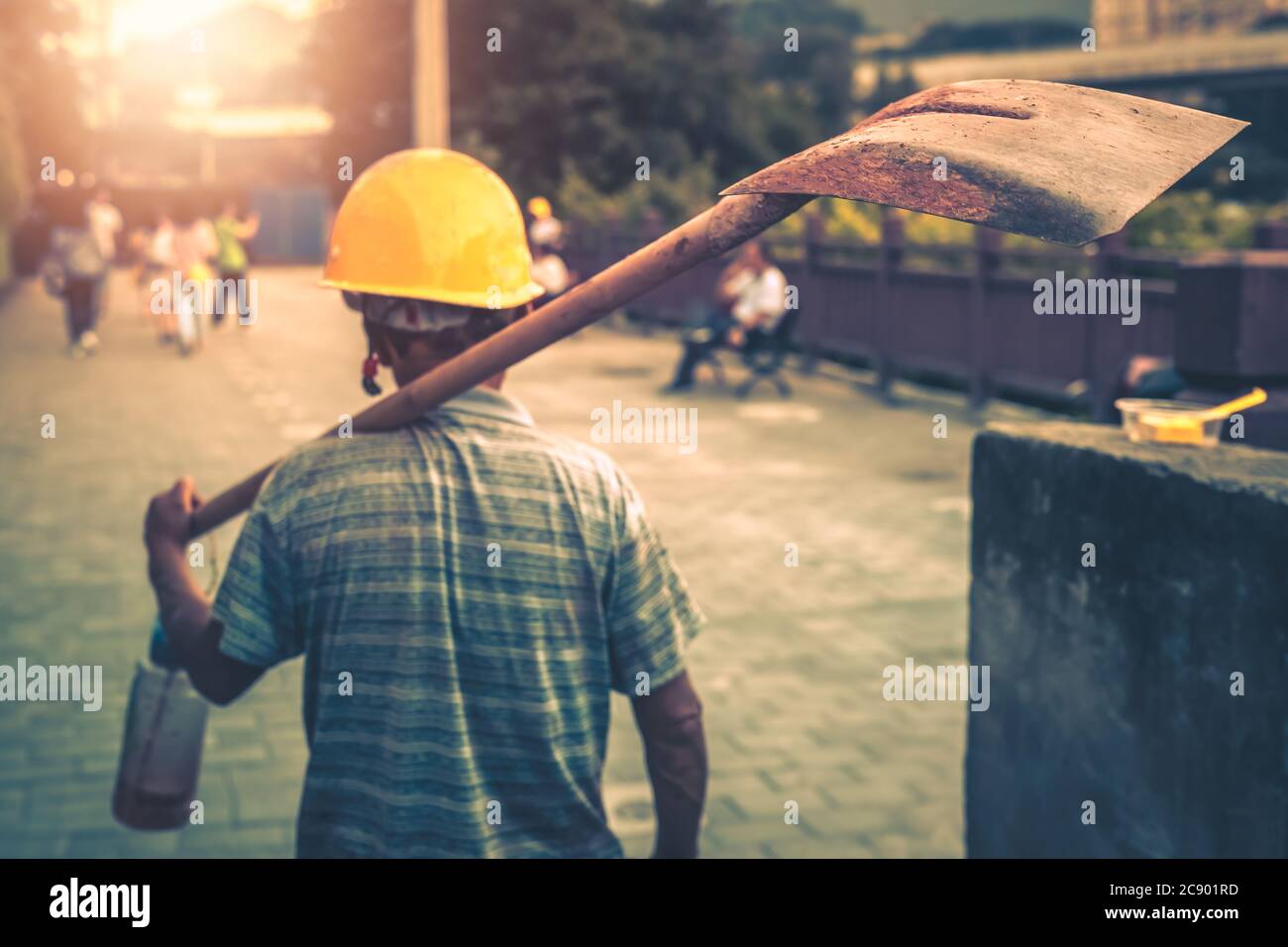 Chinese worker carrying his shovel on his arm and going home after finishing his work shift ...