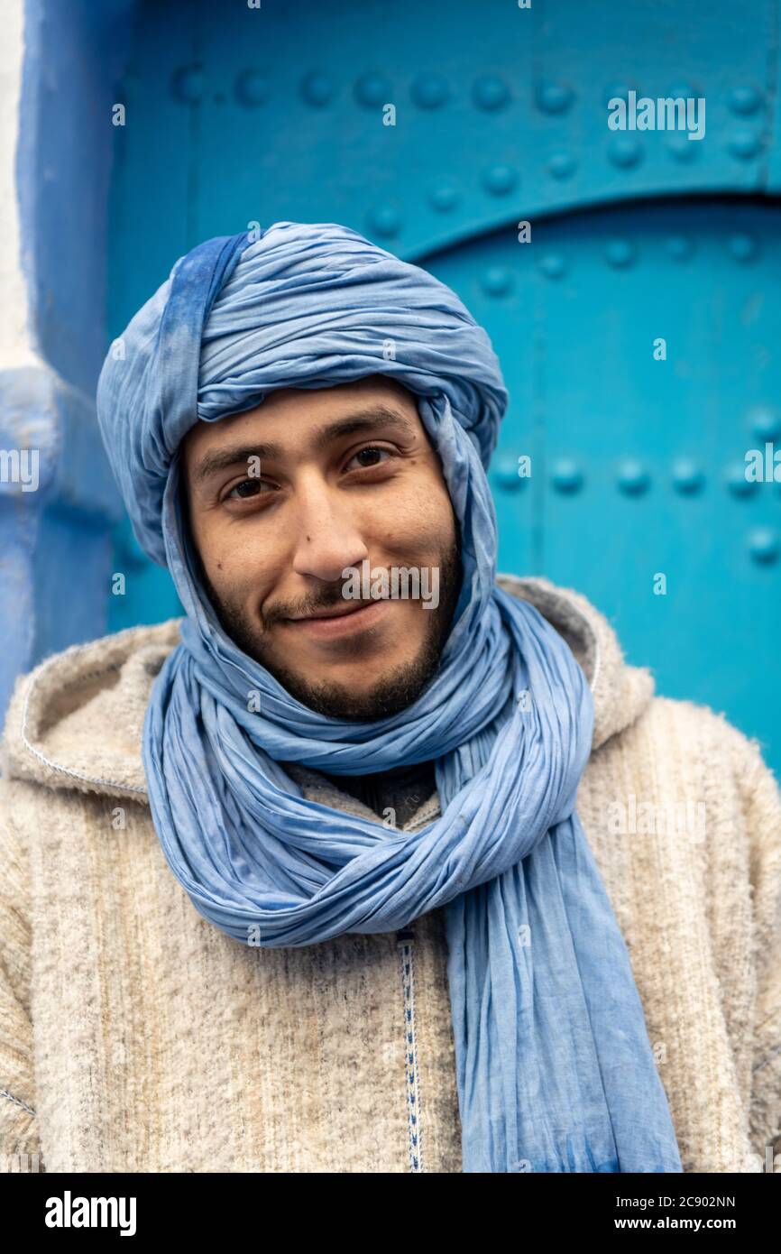 A young Berber with blue turban sells his wares in the city of ...