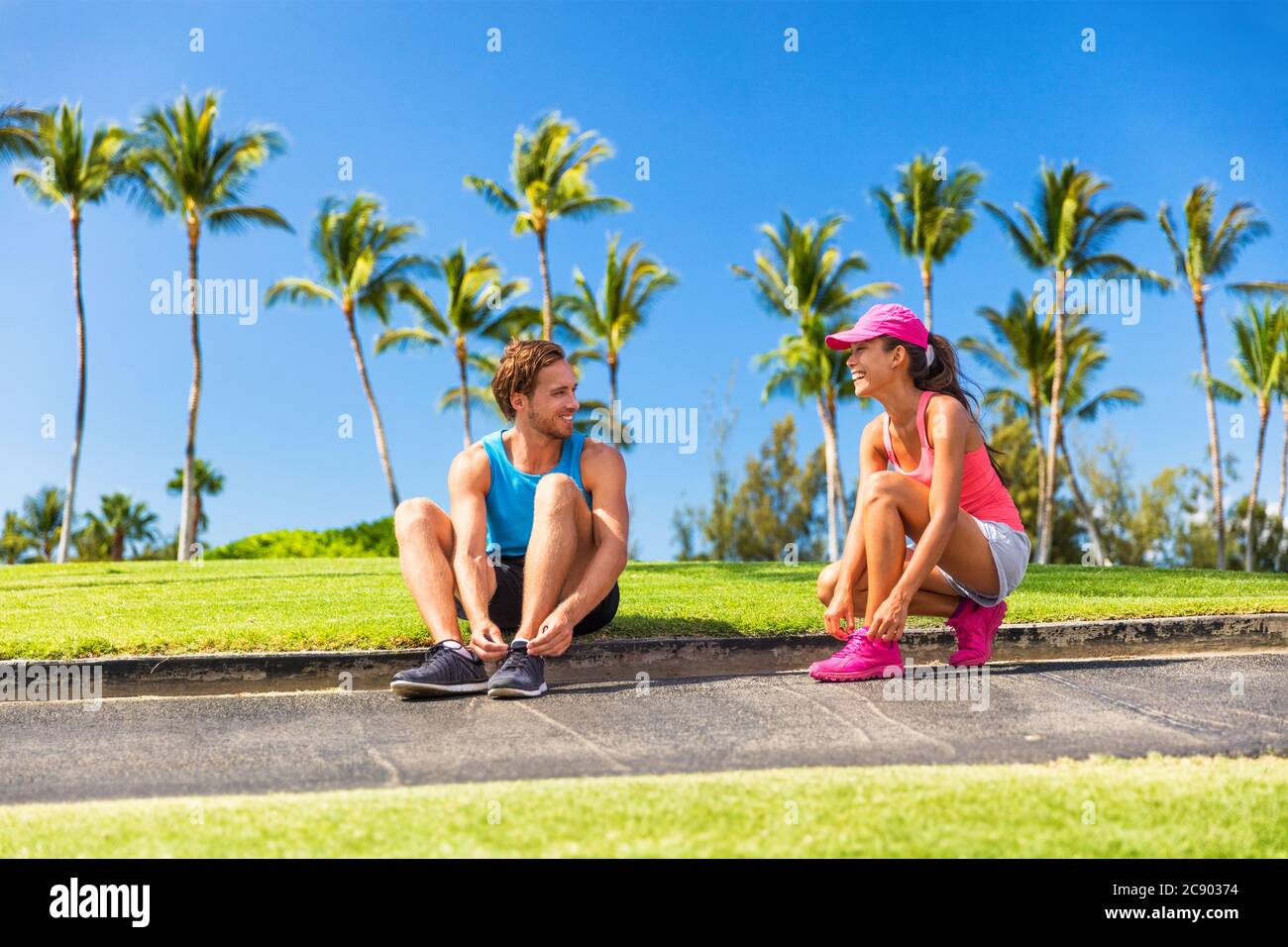 Runners tying running shoes getting ready to run. Runner woman and athlete man lacing shoe laces ...