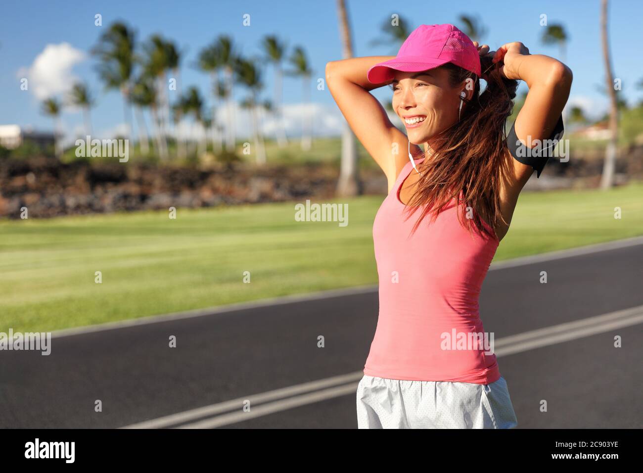 Active Asian runner woman tying hair into ponytail getting ready to run ...