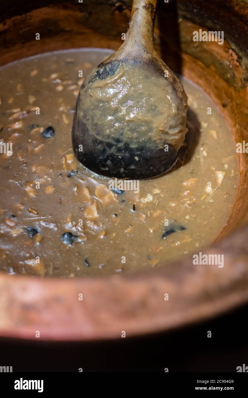 Large ladle mixing seafood stew in a old traditional ceramic pot in the ...