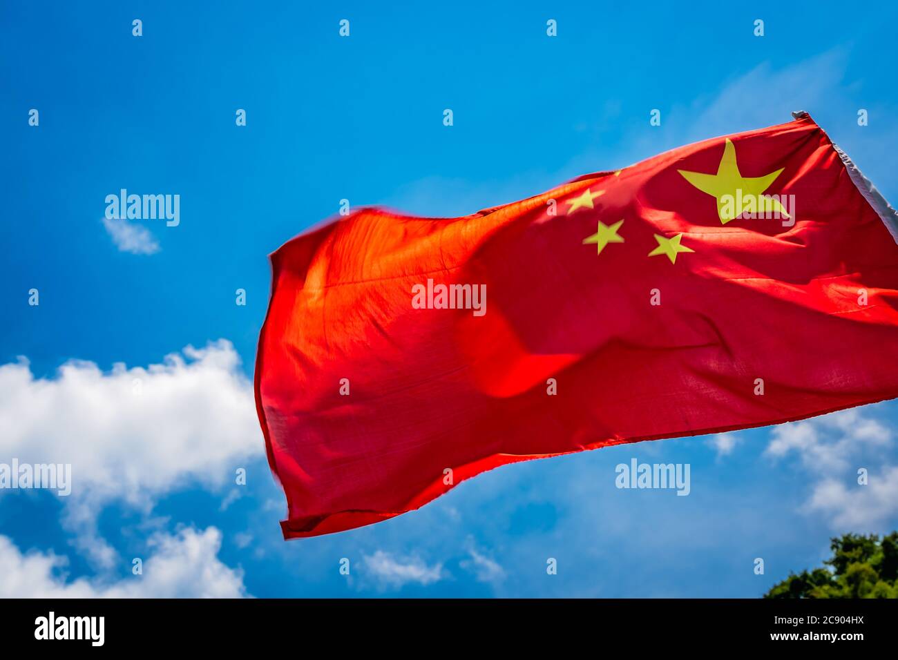 Red Chinese national flag fluttering on a mast with a blue sky ...