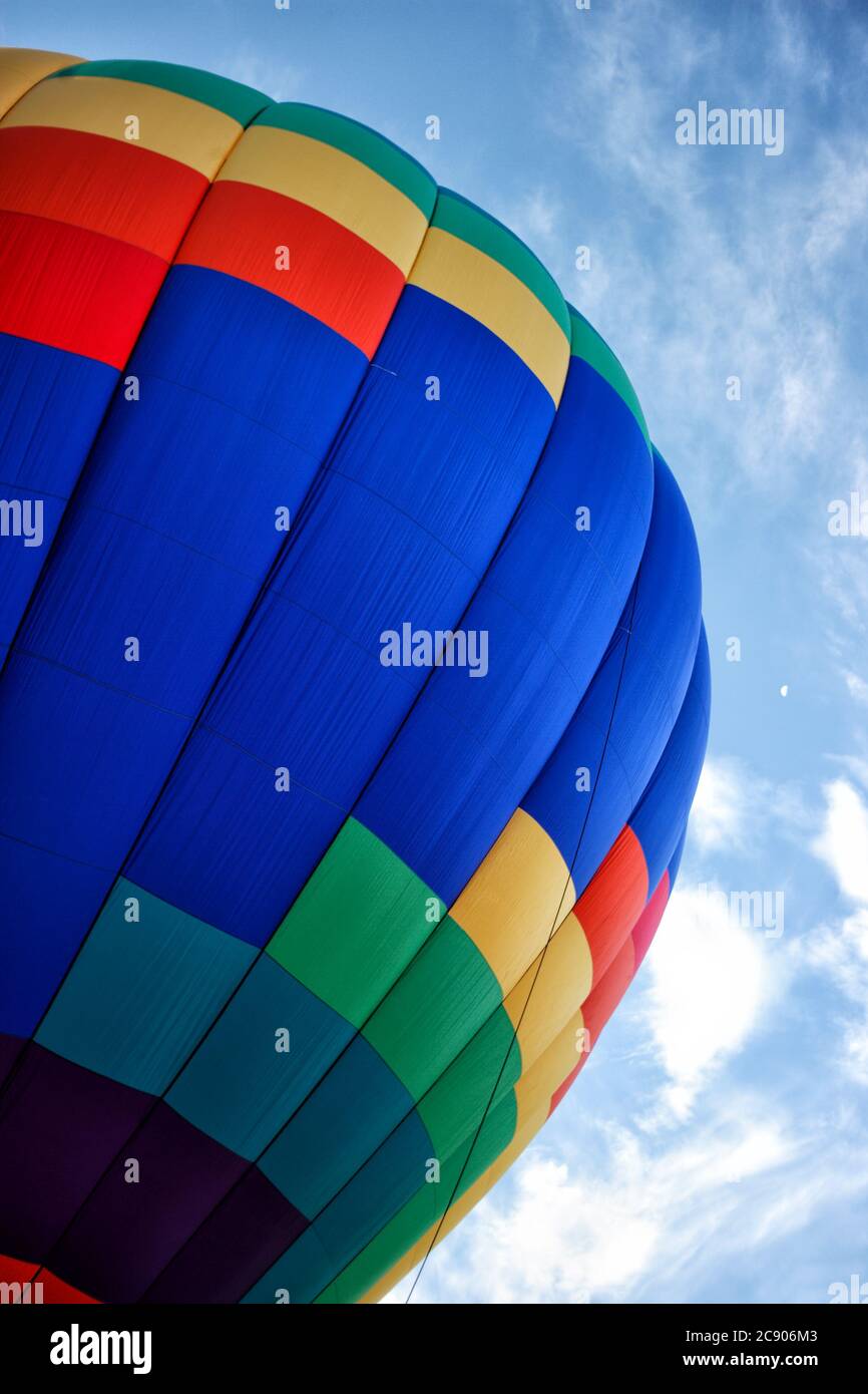An ground view of a hot air balloon against a blue sky, floating over ...
