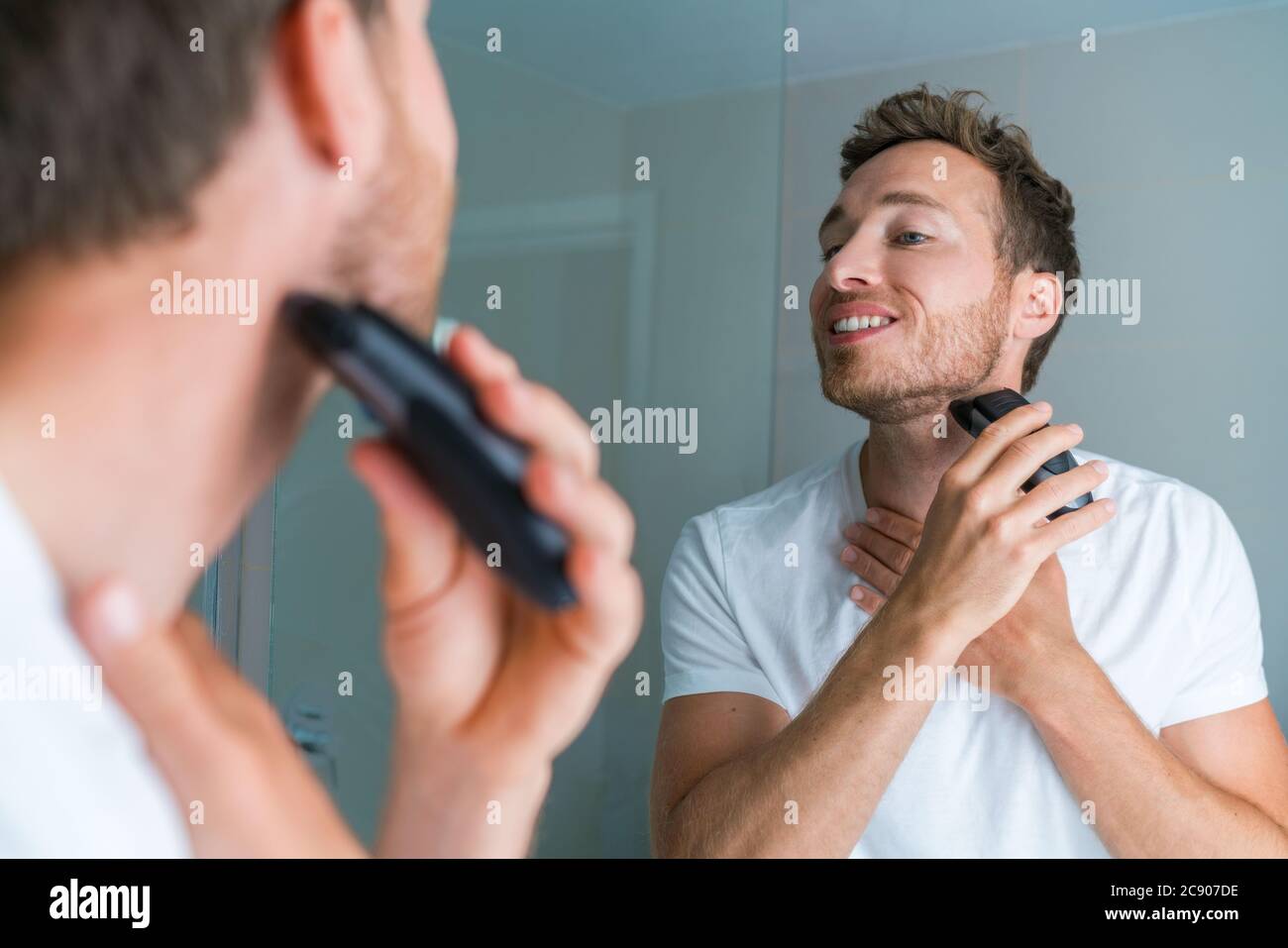 Young man shaving neck and jawline in the morning using electric shaver ...