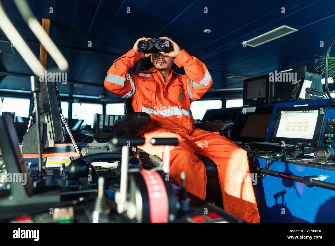 Filipino deck Officer on bridge of vessel or ship looking through ...