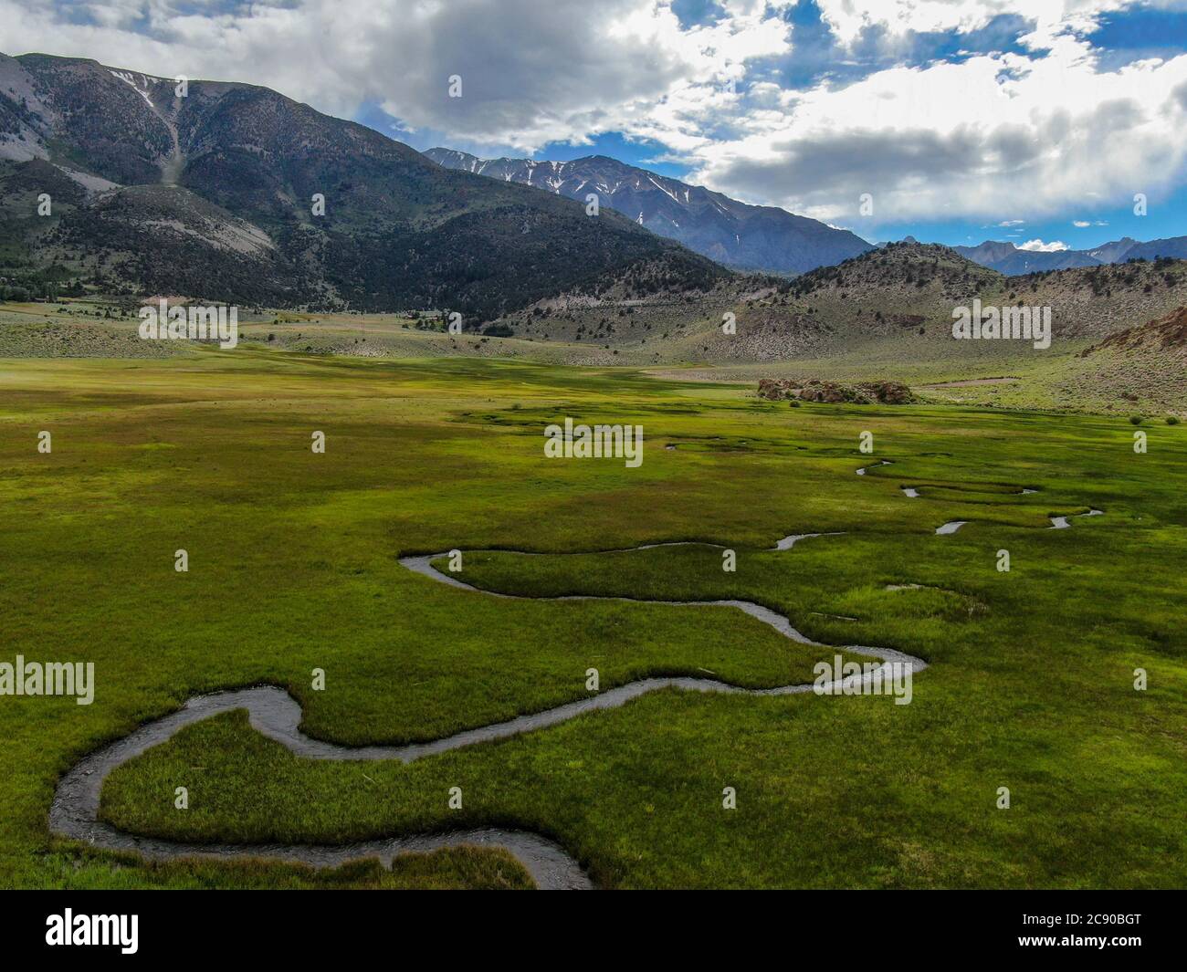 Aerial view of green land and small curve river with mountain in the ...