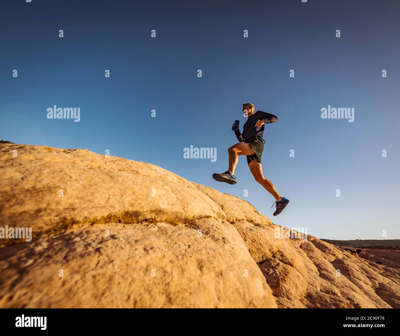 USA, Utah, St. George, Man jumping while running in rocky landscape ...
