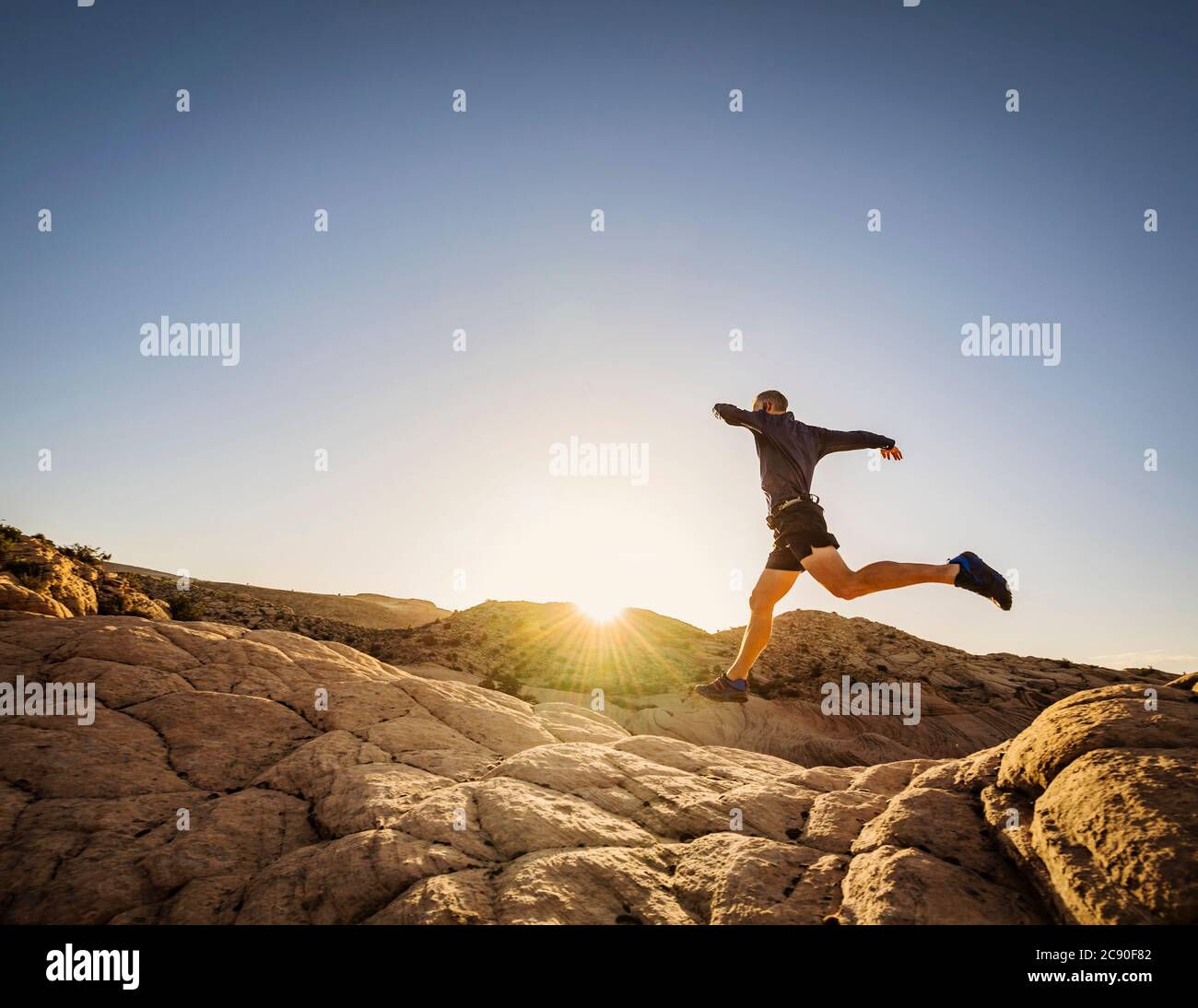 USA, Utah, St. George, Man jumping while running in rocky landscape ...
