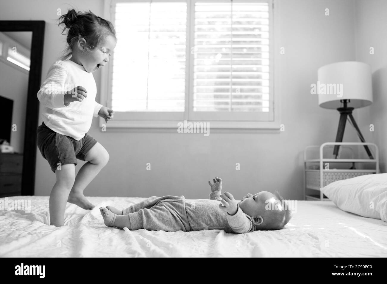 Toddler sister playing on bed with her baby brother Stock Photo - Alamy