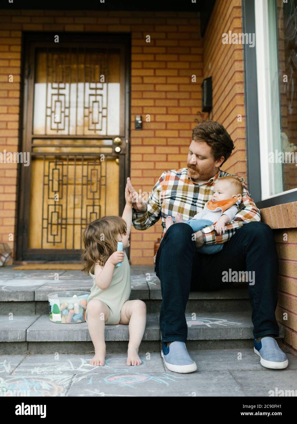 Father with kids sitting on porch Stock Photo - Alamy
