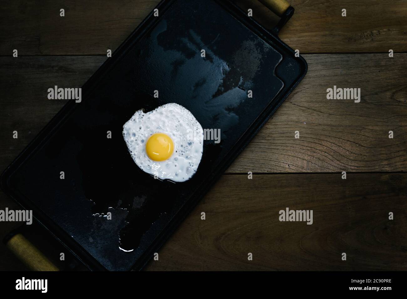 Fried egg white and yolk on rectangular cast iron flat griddle pan with ...