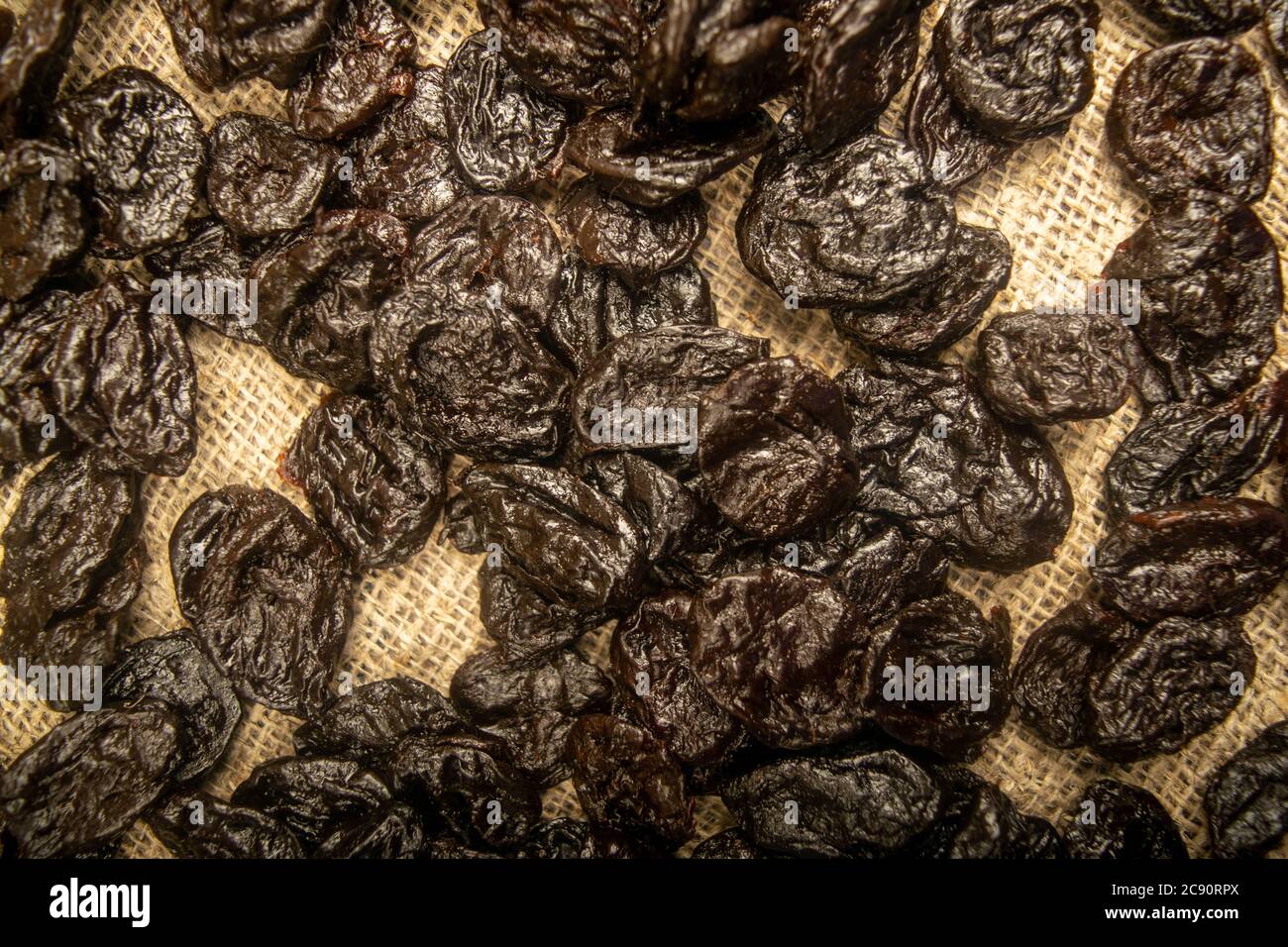 Dried prunes in bulk on burlap with a rough texture. Close up Stock ...