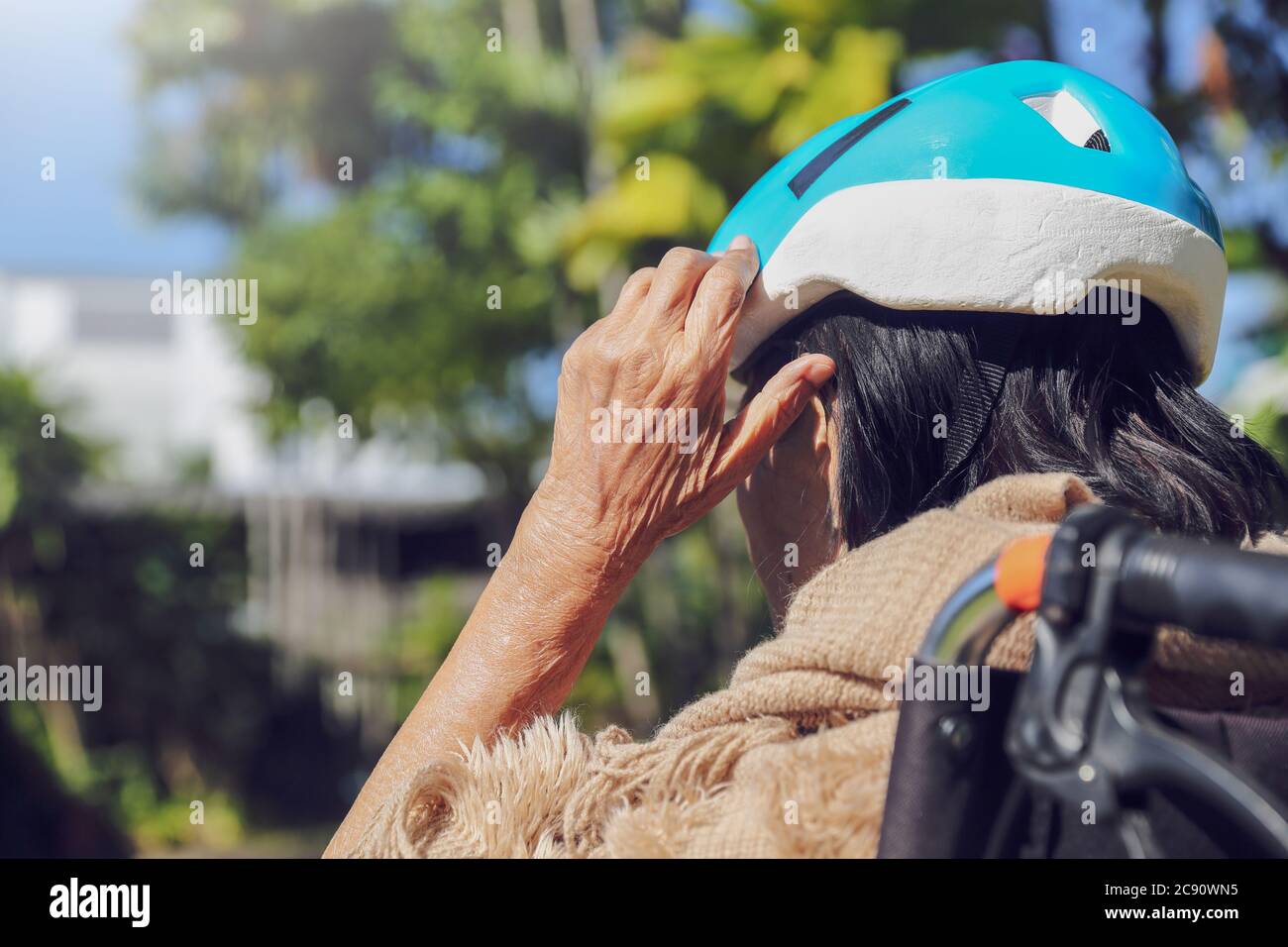 elderly woman in backyard puts on a safety head protection helmet from ...