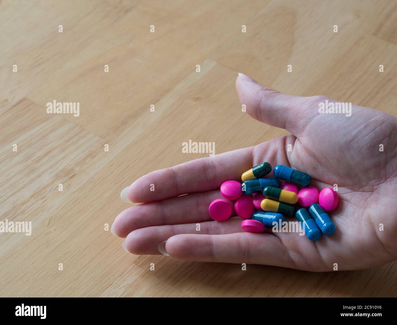 women hand full of colorful blue green yellow and pink pills pain ...