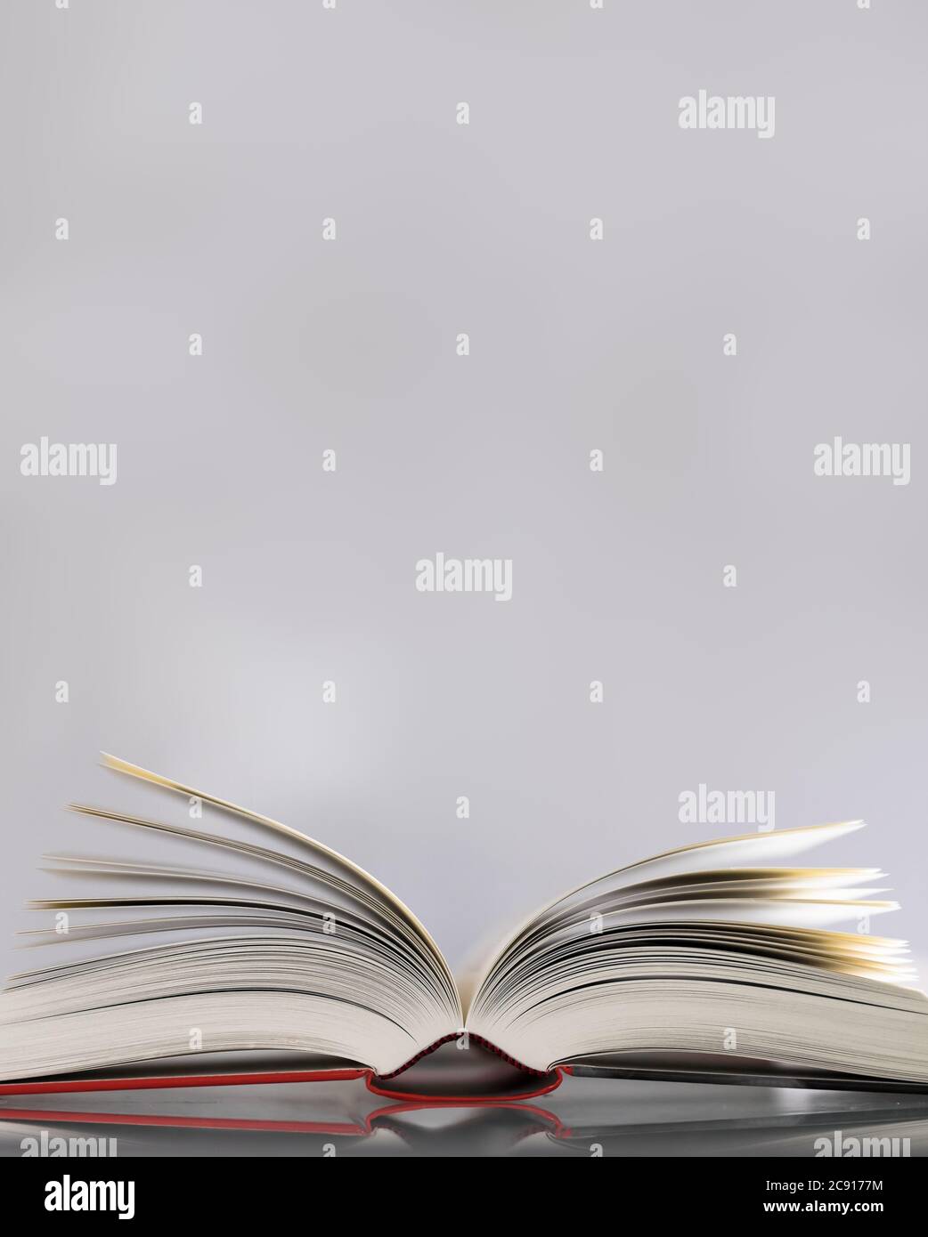 Open book with red cover and narrow depth of field on light background ...
