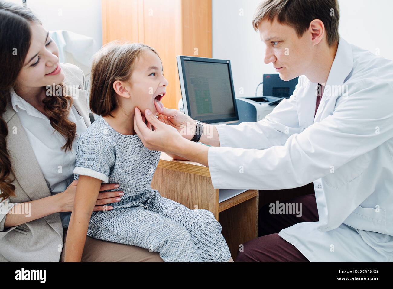 Male pediatrician examining little girl's tonsils in his office Stock ...