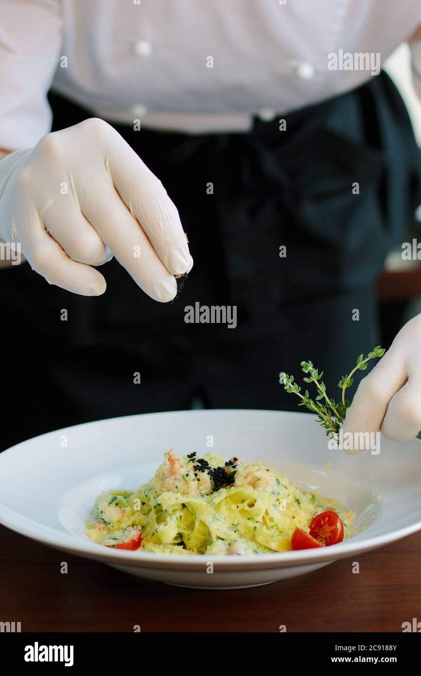 Chief dressing pasta with black truffle and herbs Stock Photo - Alamy