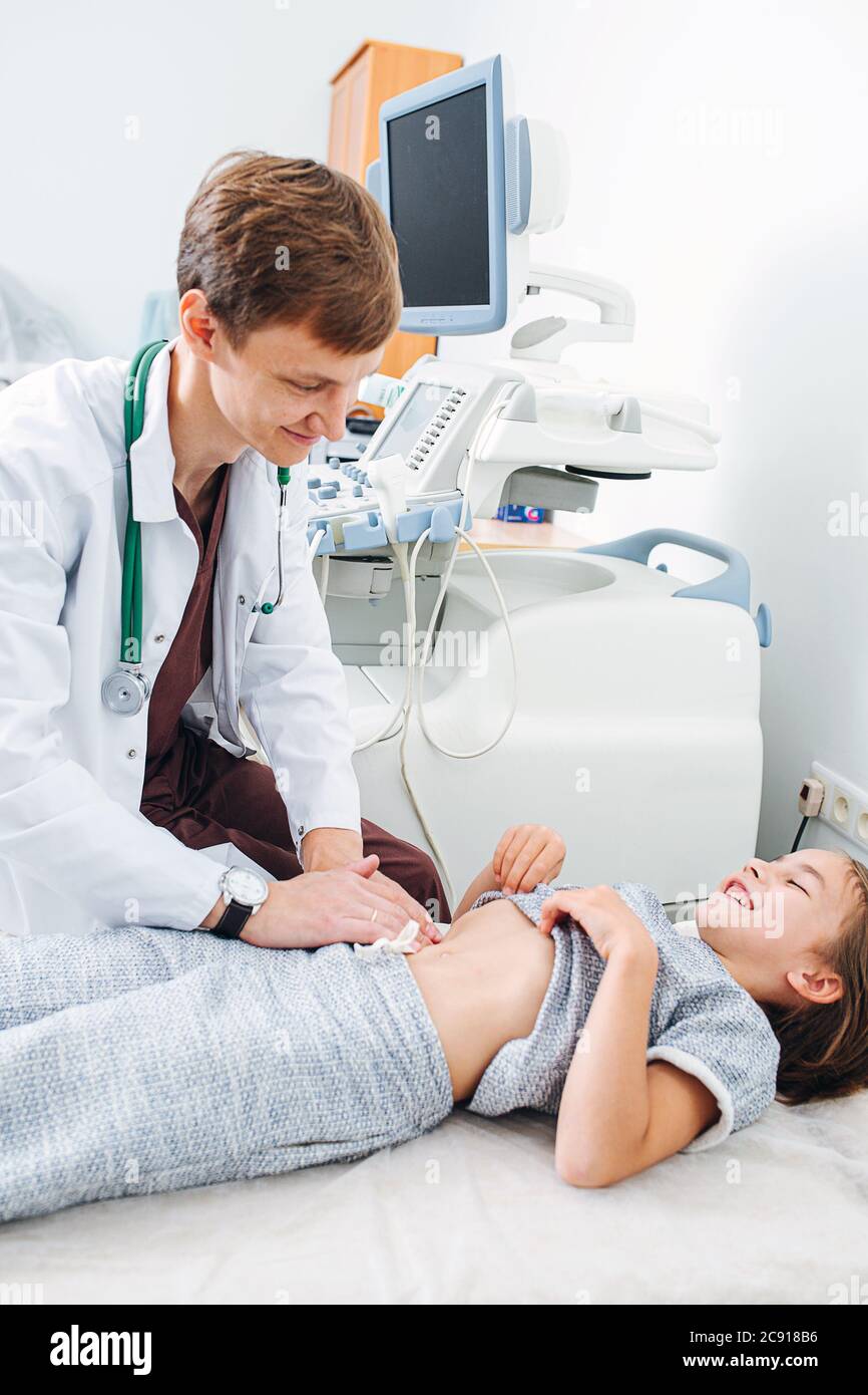 Friendly doctor pressing his fingers against stomach of a little girl ...