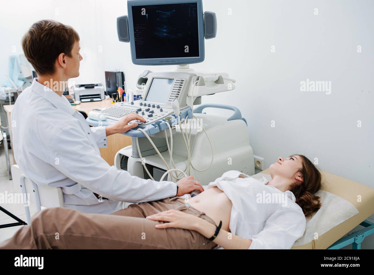 US specialist performing ultrasound scan on a young female patient ...