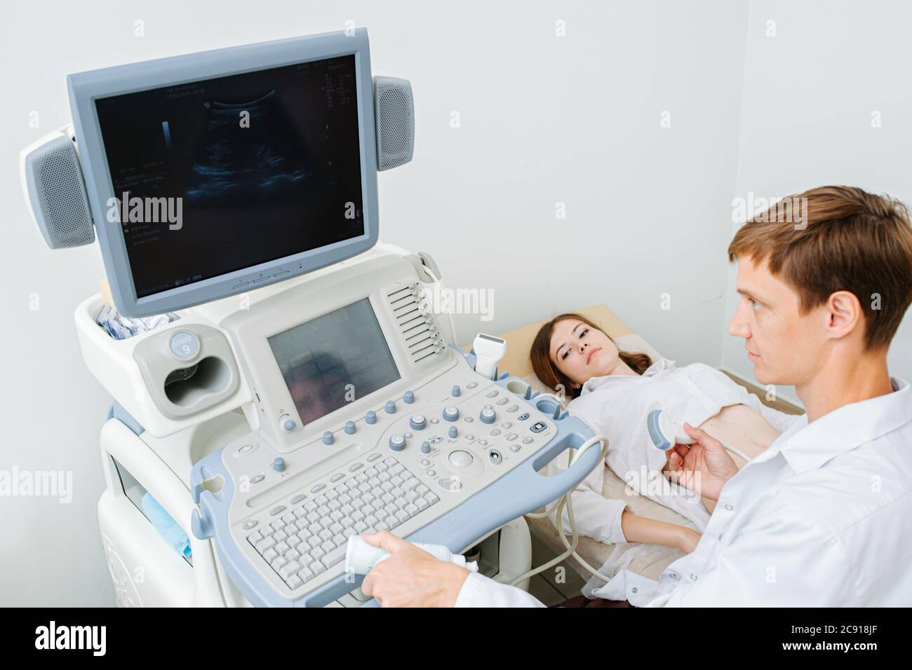 Attentive doctor performing ultrasound scan on a young female patient ...