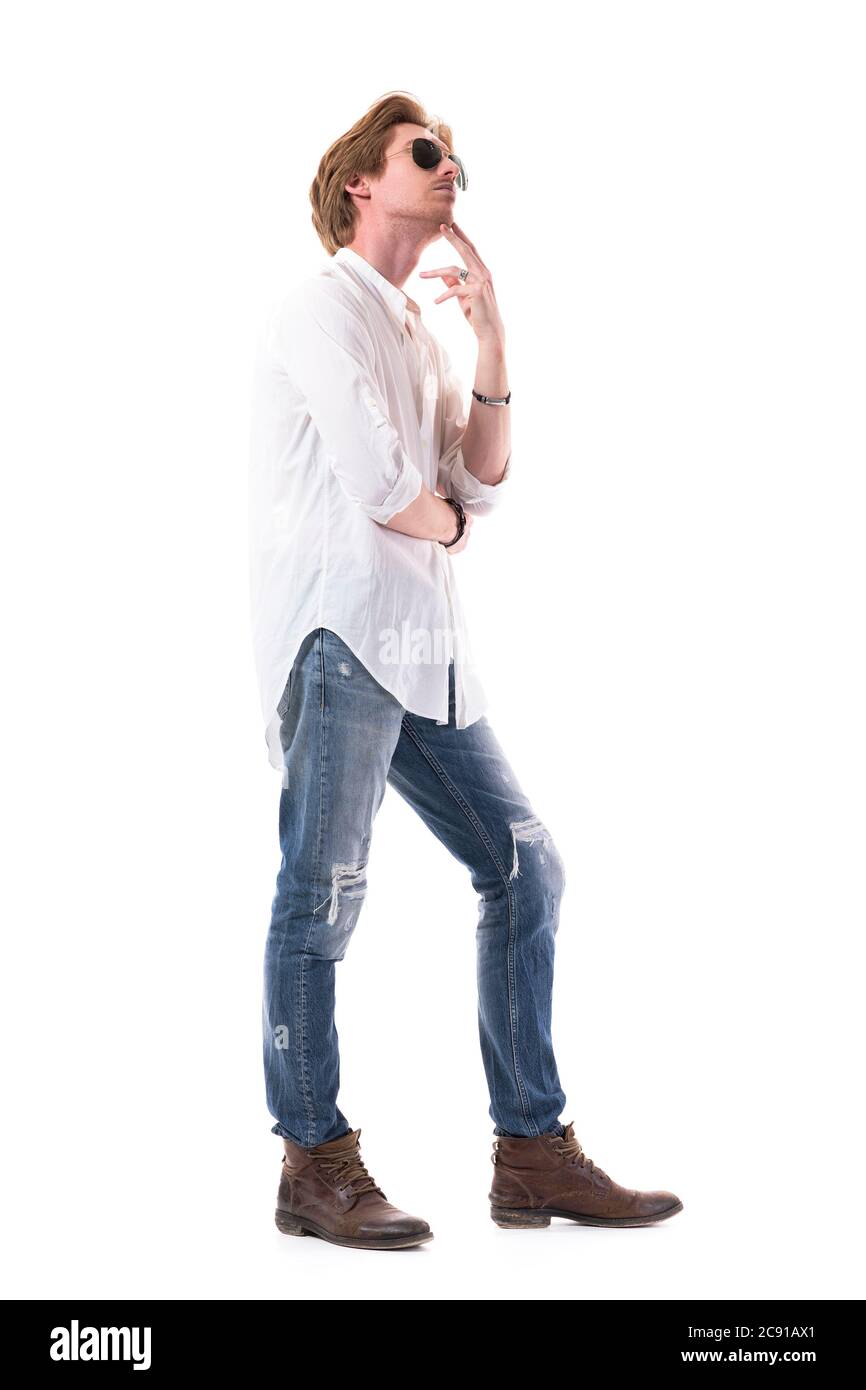 Side view of thoughtful young man with finger on chin looking up ...