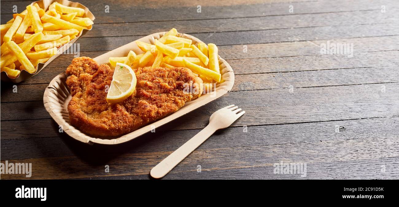 Serving of crumbed fried fish or schnitzel with French fries and a ...