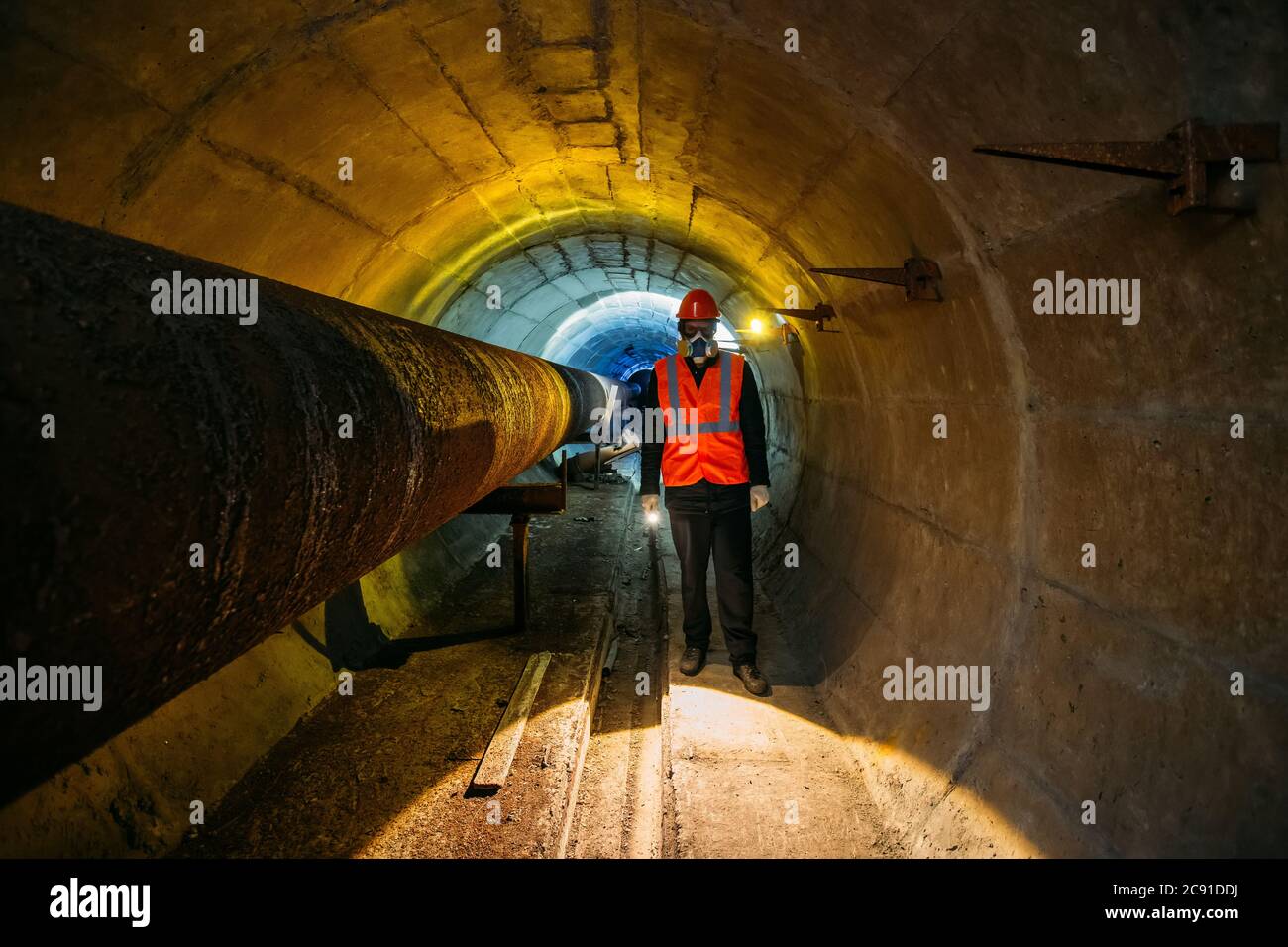 Tunnel worker examines pipeline in underground tunnel Stock Photo - Alamy