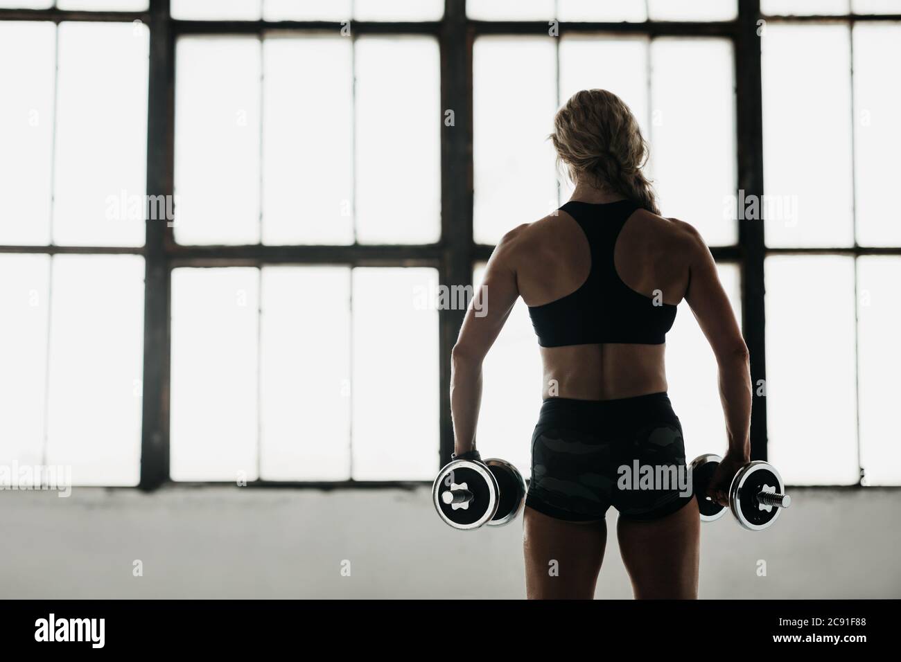 Beautiful muscular athlete, back. Woman looks out the window and do ...