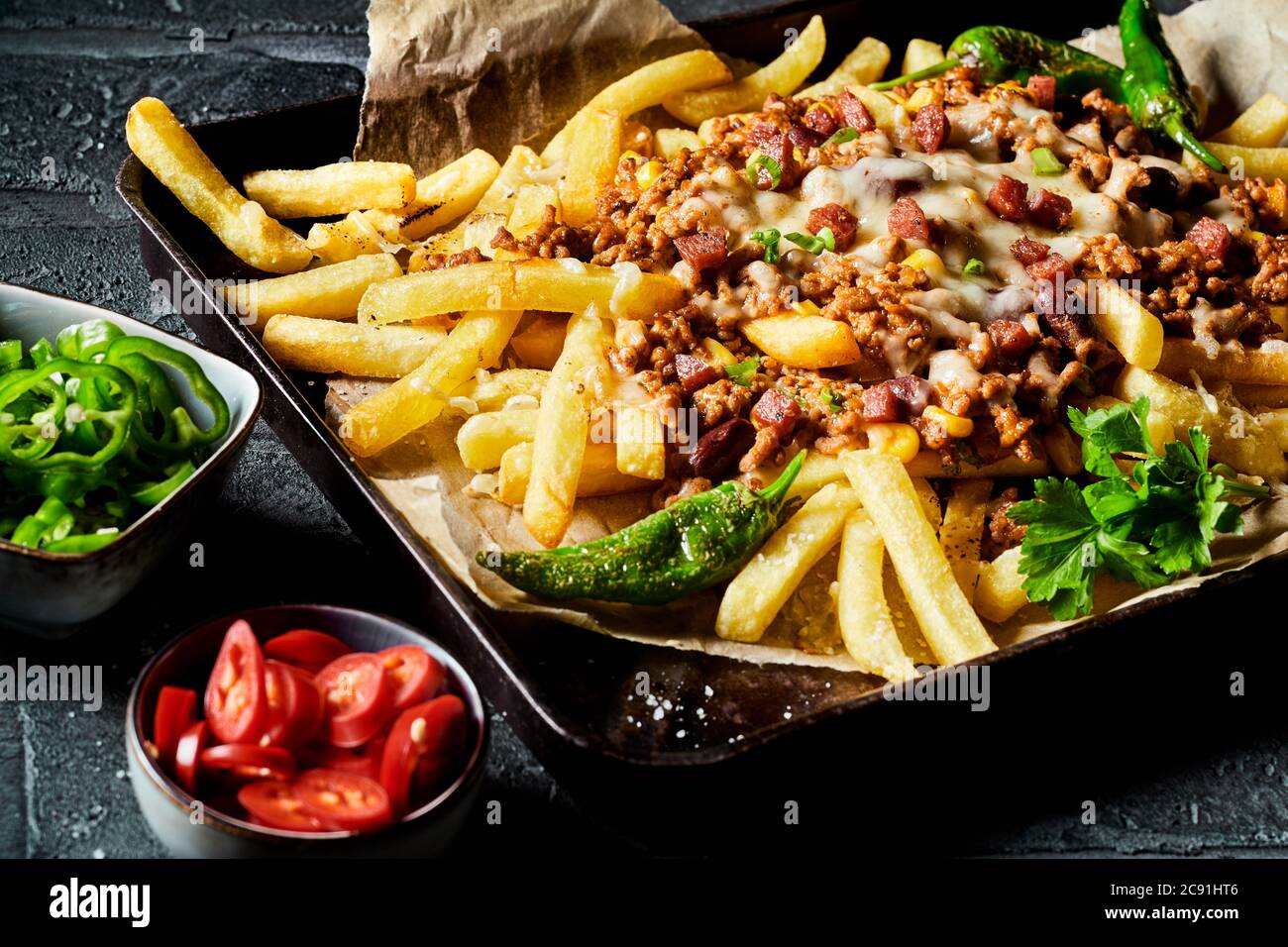 Serving of crispy French fries topped with minced beef, chili peppers ...