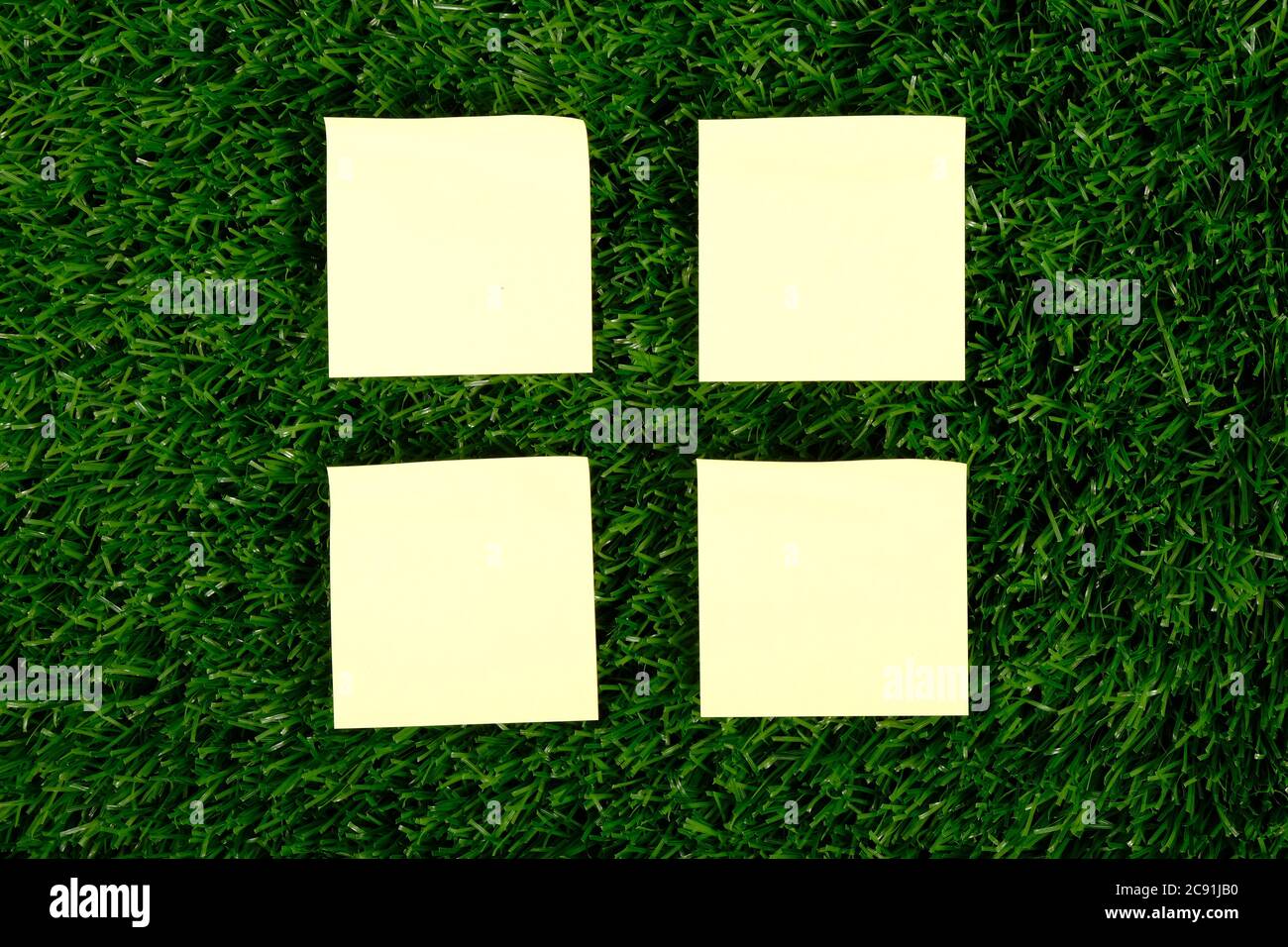 yellow paper rectangular stickers on green grass top view. copy space ...