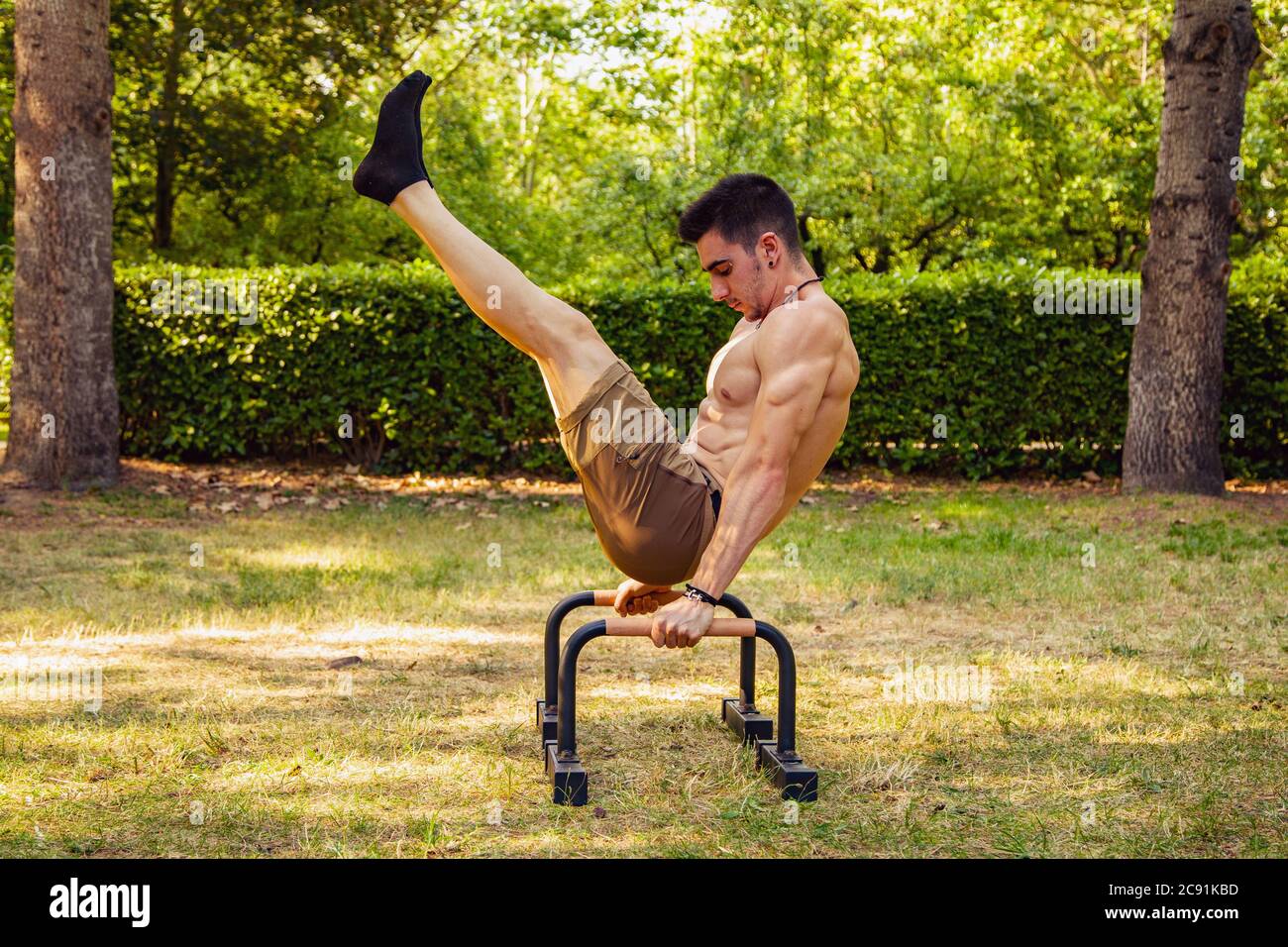 Shirtless muscular man doing calisthenics at a park Stock Photo - Alamy
