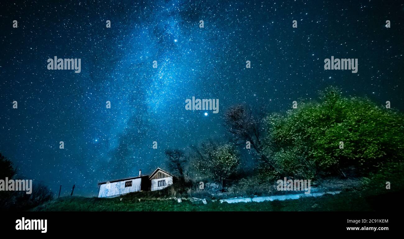 Starry night sky over a small house and trees Stock Photo - Alamy