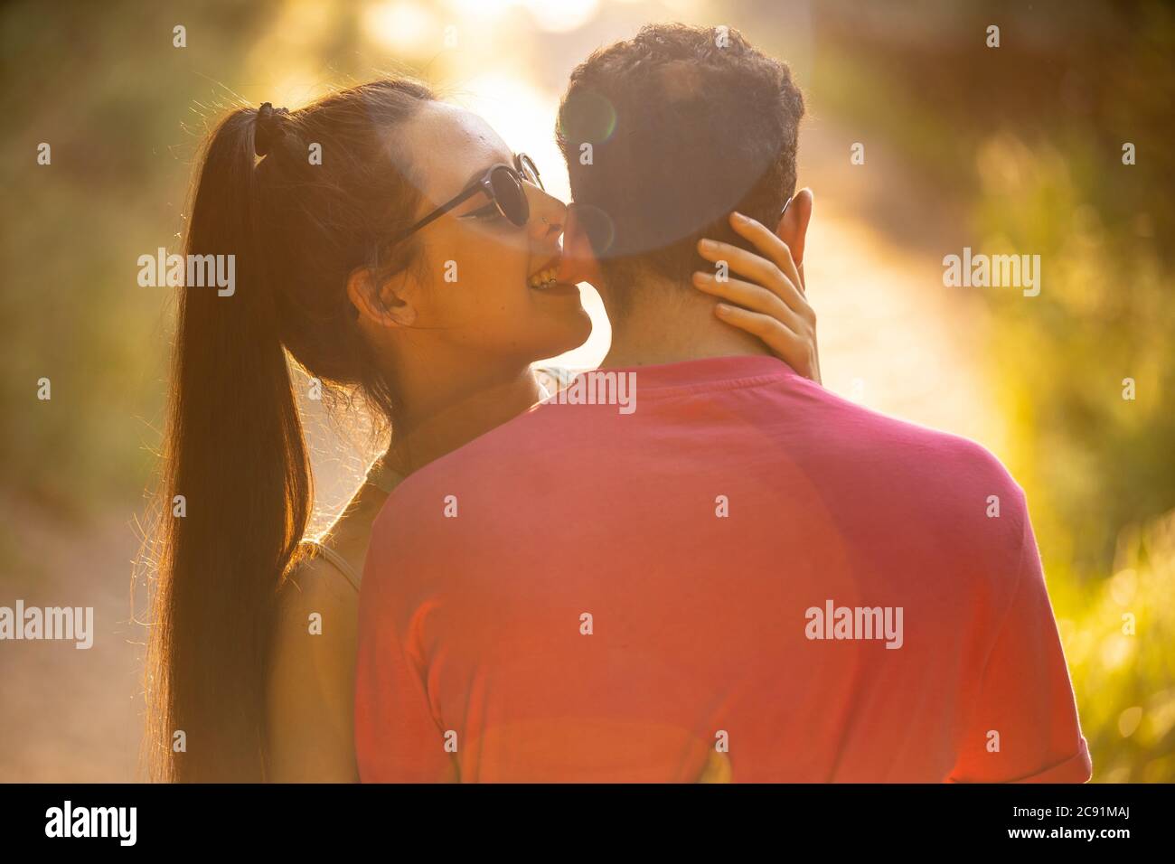 Romantic shot of a couple where the female is playfully biting the ear ...