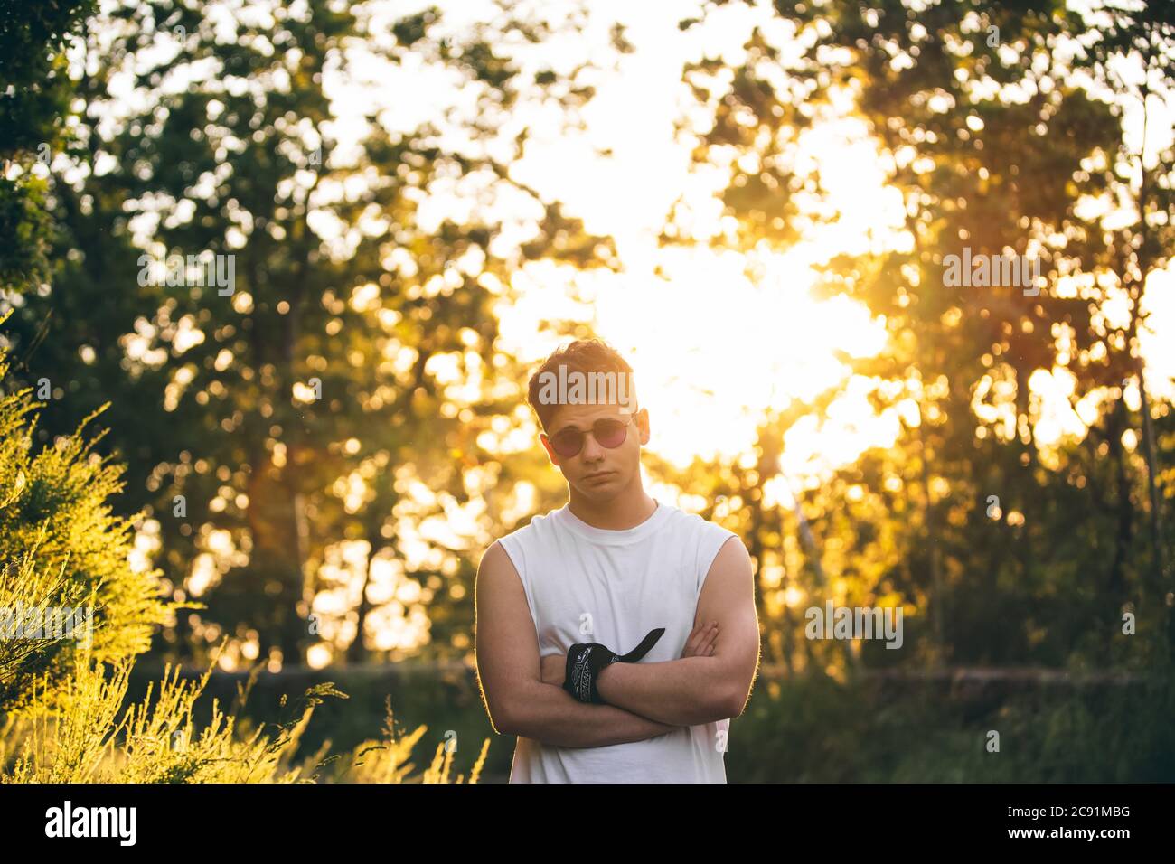 Male wearing white muscle tee shirt and sunglasses with his arms folded ...